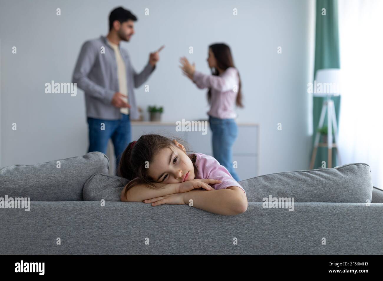 Family conflicts. Sad arab girl sitting alone while her parents arguing ...