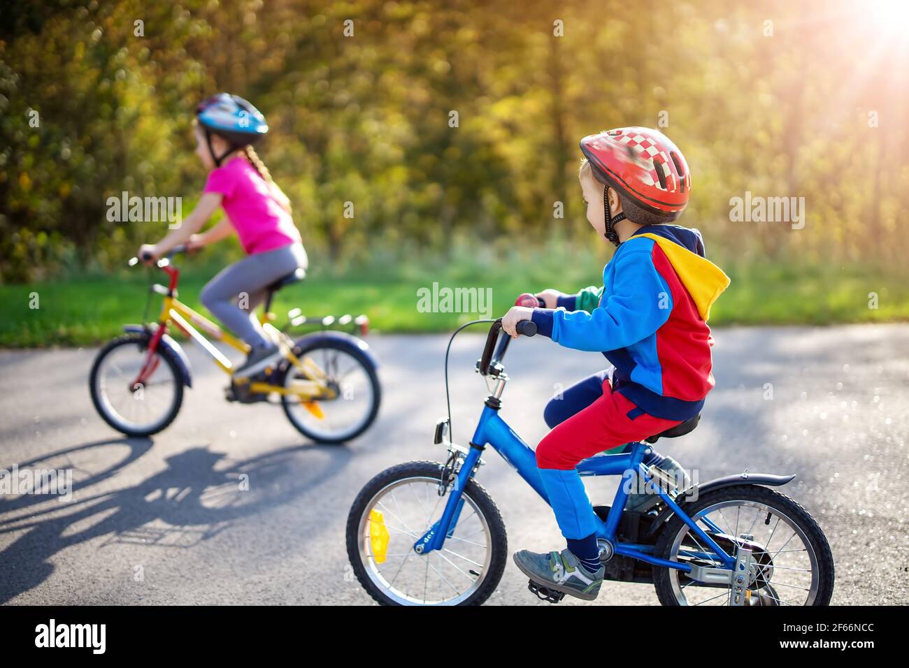 Cute children riding on bicycles on asphalt road in summer Stock Photo ...