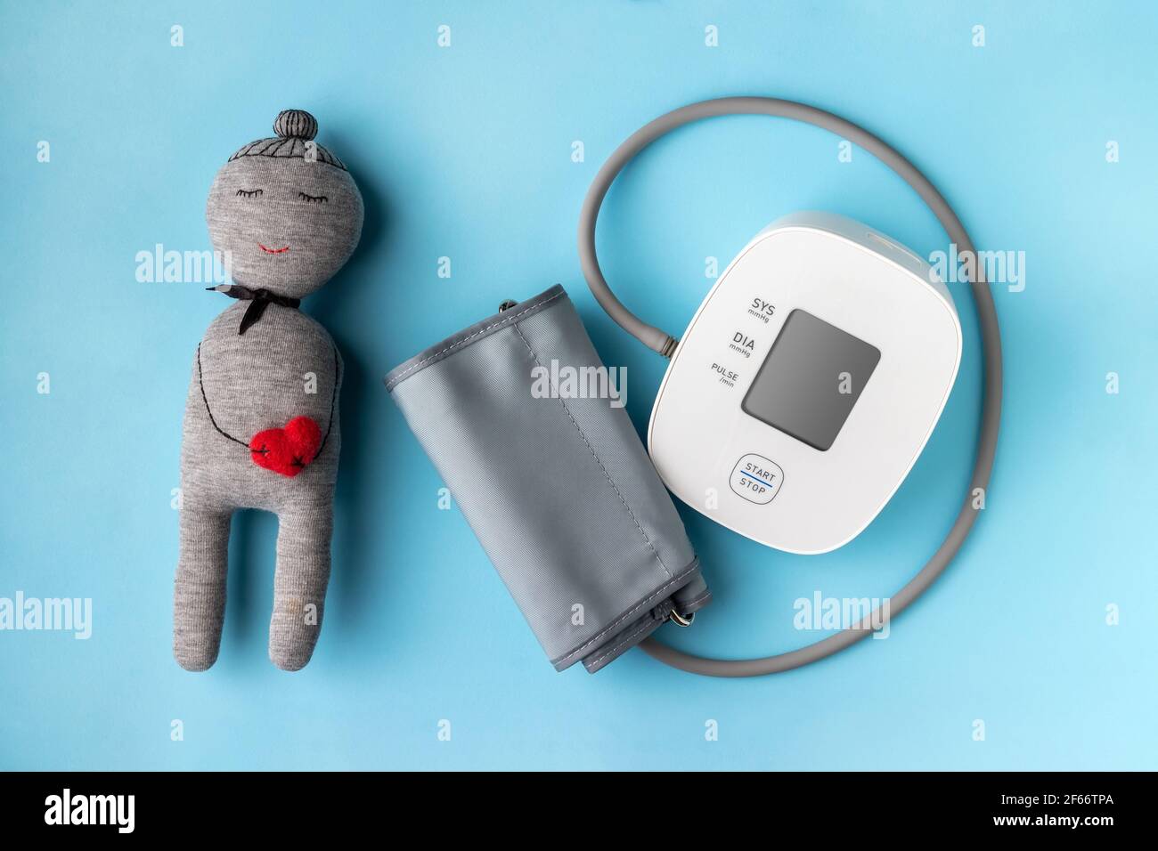 Automatic blood pressure monitor and cute soft toy with heart on blue ...