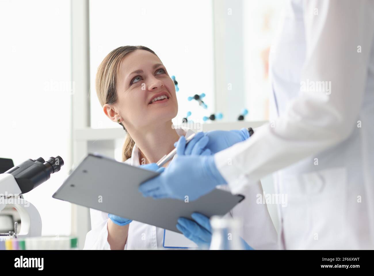 Assistant giving woman chemist clipboard with documents in lab Stock ...