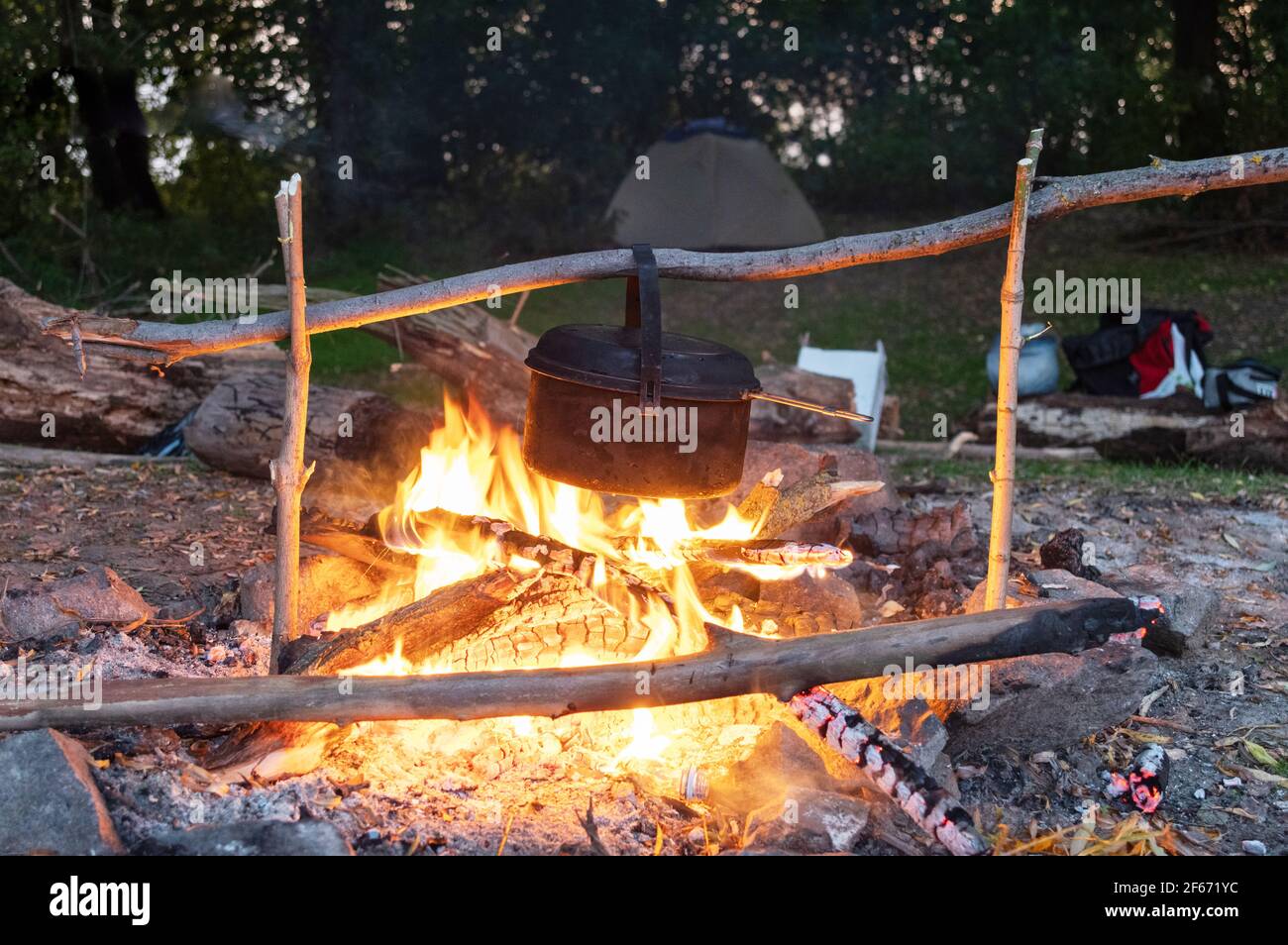 A saucepan hanging over the fire. Picnic with barbecue. Evening bonfire ...