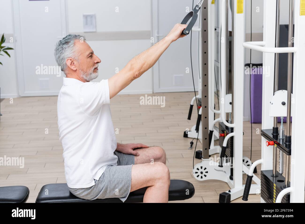side view of middle aged man exercising on pull cable machine during ...