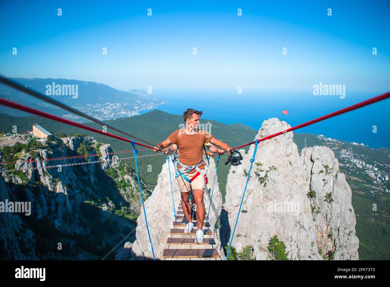 Man crossing the chasm on the rope bridge Stock Photo - Alamy