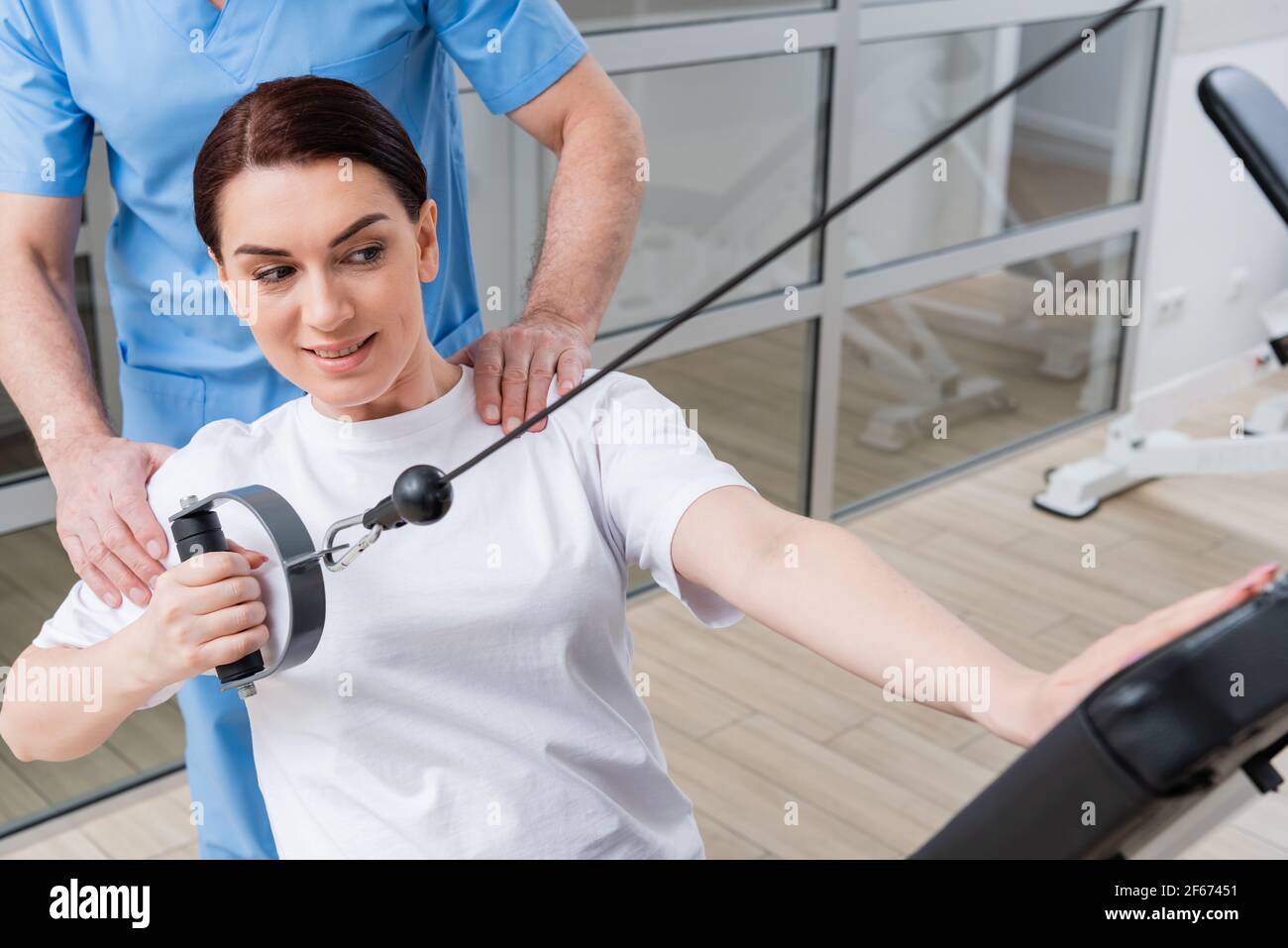 trainer assisting woman working on pull cable exercising machine Stock ...