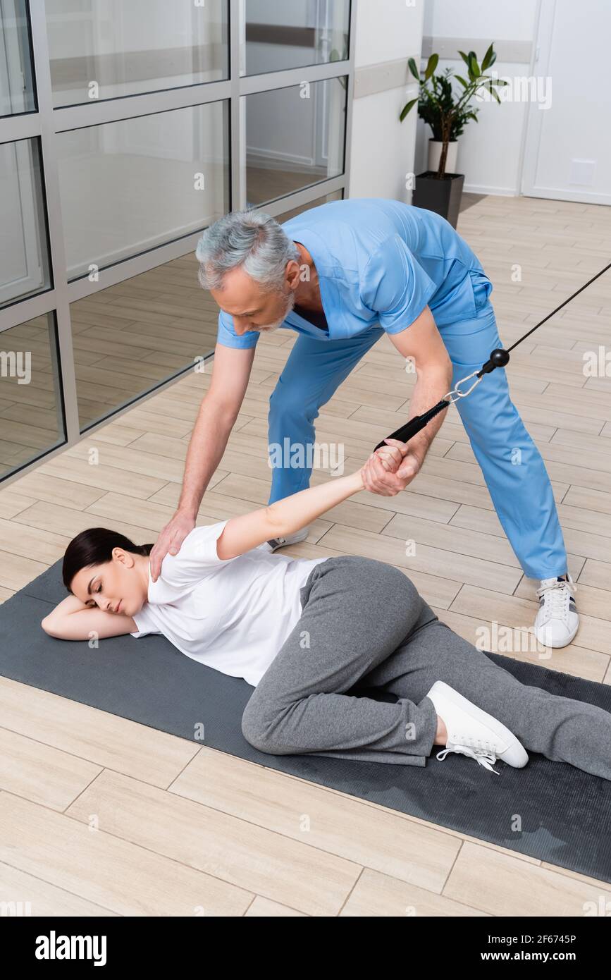 mature physiotherapist helping woman working out in rehabilitation ...