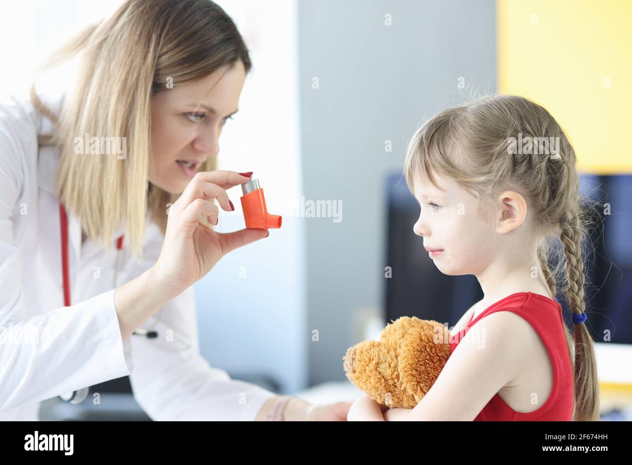 Pulmonologist doctor holding hormonal inhaler in front of little girl ...