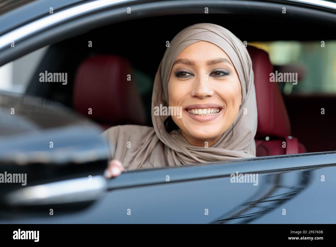Smiling muslim woman test driving car in urban city Stock Photo - Alamy