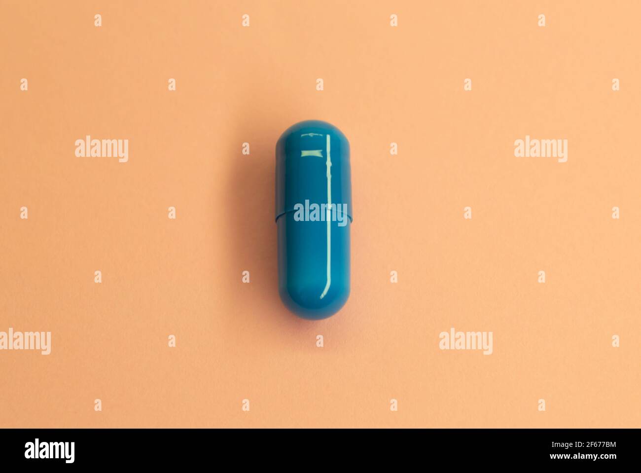 one blue medical capsule on a peach background Stock Photo - Alamy