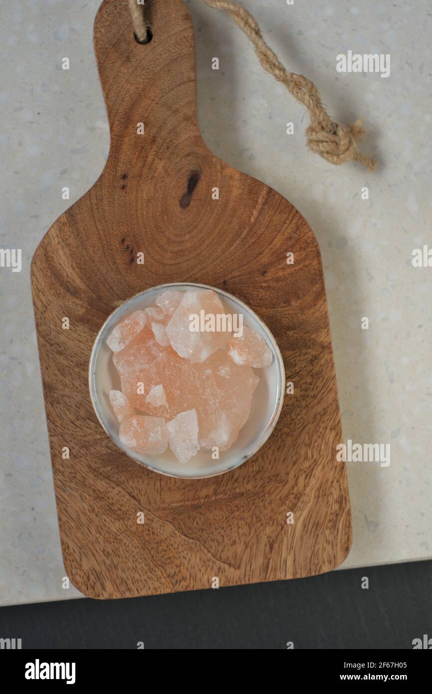 Himalayan pink salt in gray cup on wooden board on marble background ...