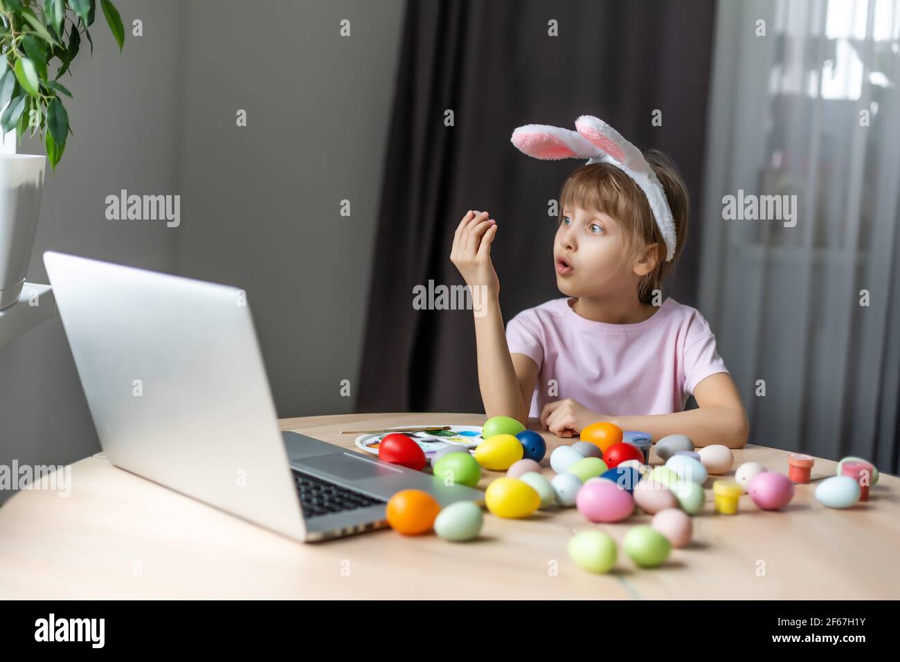 Little girl with her bunny using computer together preparing for easter ...