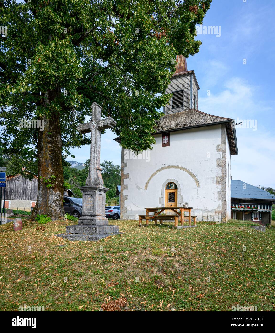 Stone religious cross under tree at small chapel. Christian landmark ...