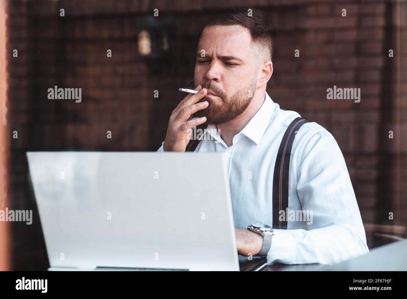 Young businessman working on a laptop in a cafe and smoking Stock Photo ...