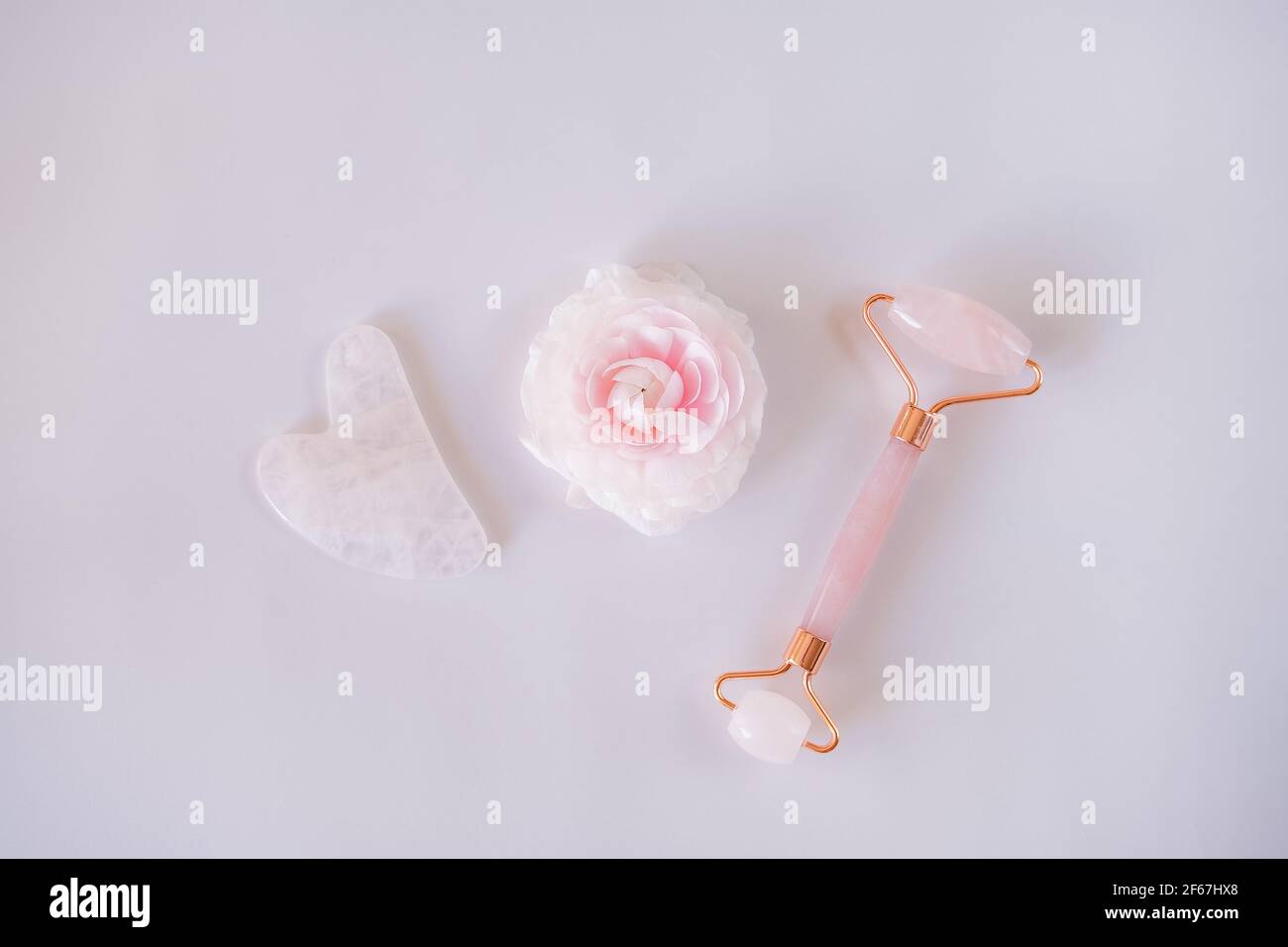 Pink Gua Sha stone and roller for massage and flower Stock Photo - Alamy