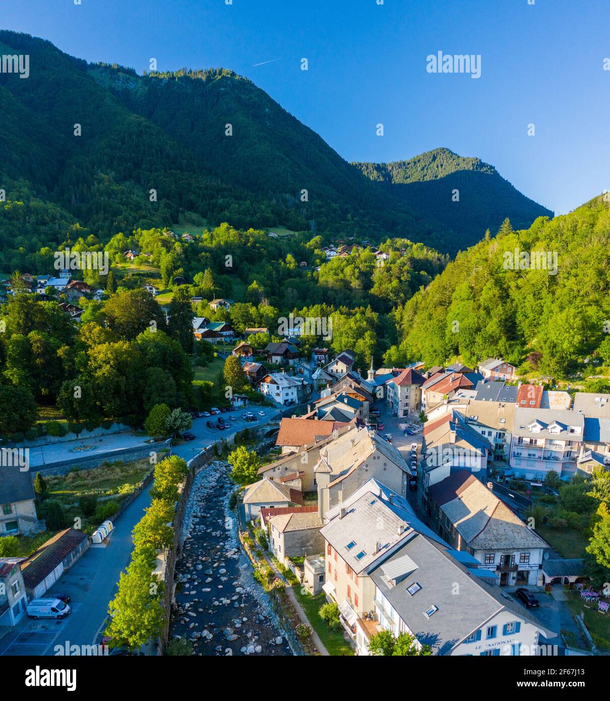 Drone view of houses in streets of Taninges town. Rising wooded ridge ...