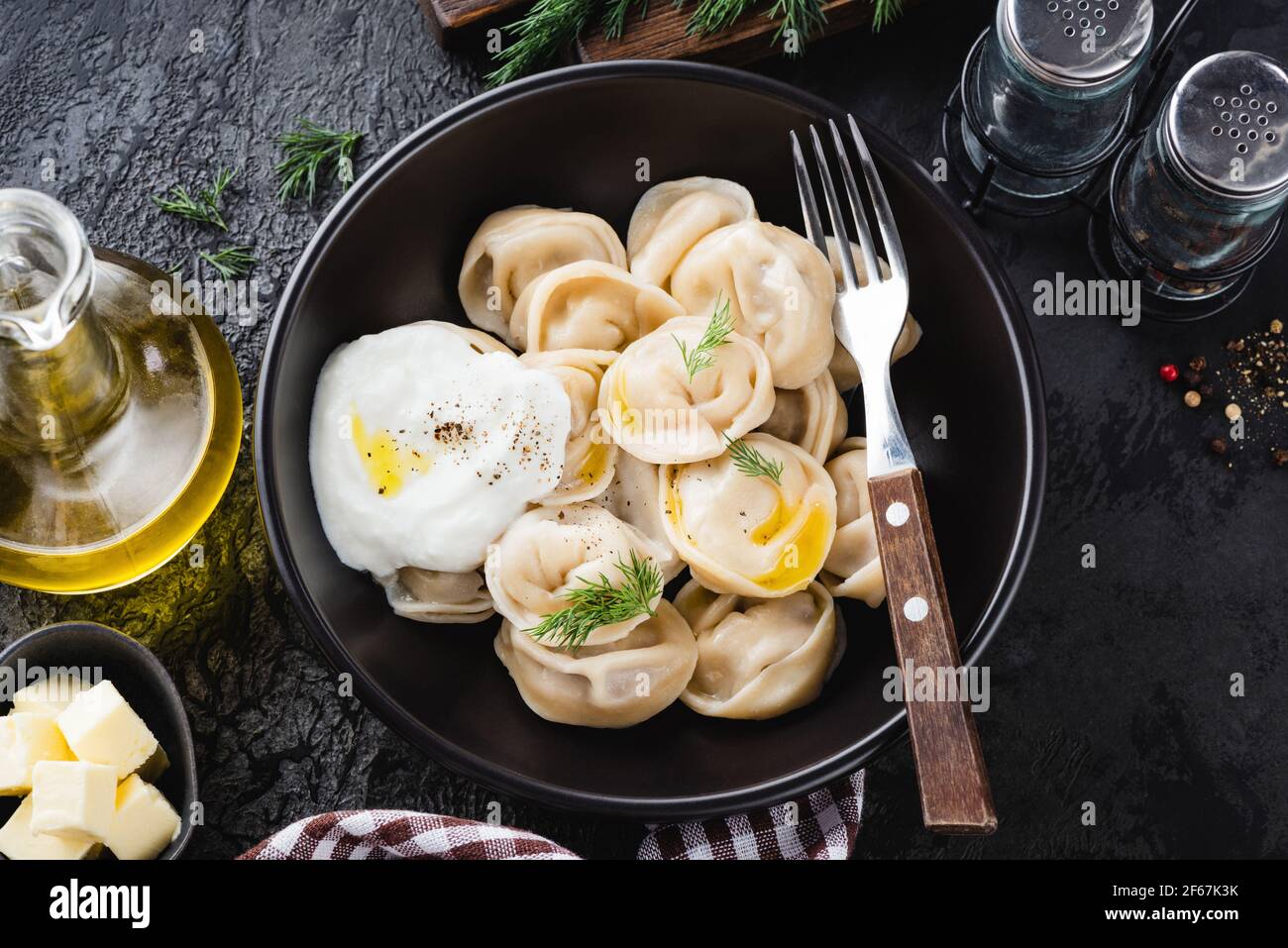 Meat dumplings, pelmeni served with butter, dill and sour cream in ...