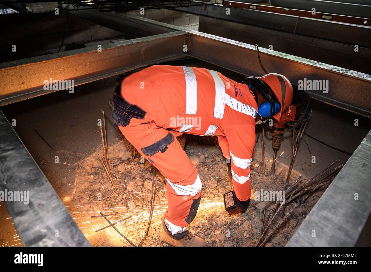 Back view on worker in protection suit cutting protruding steel ...