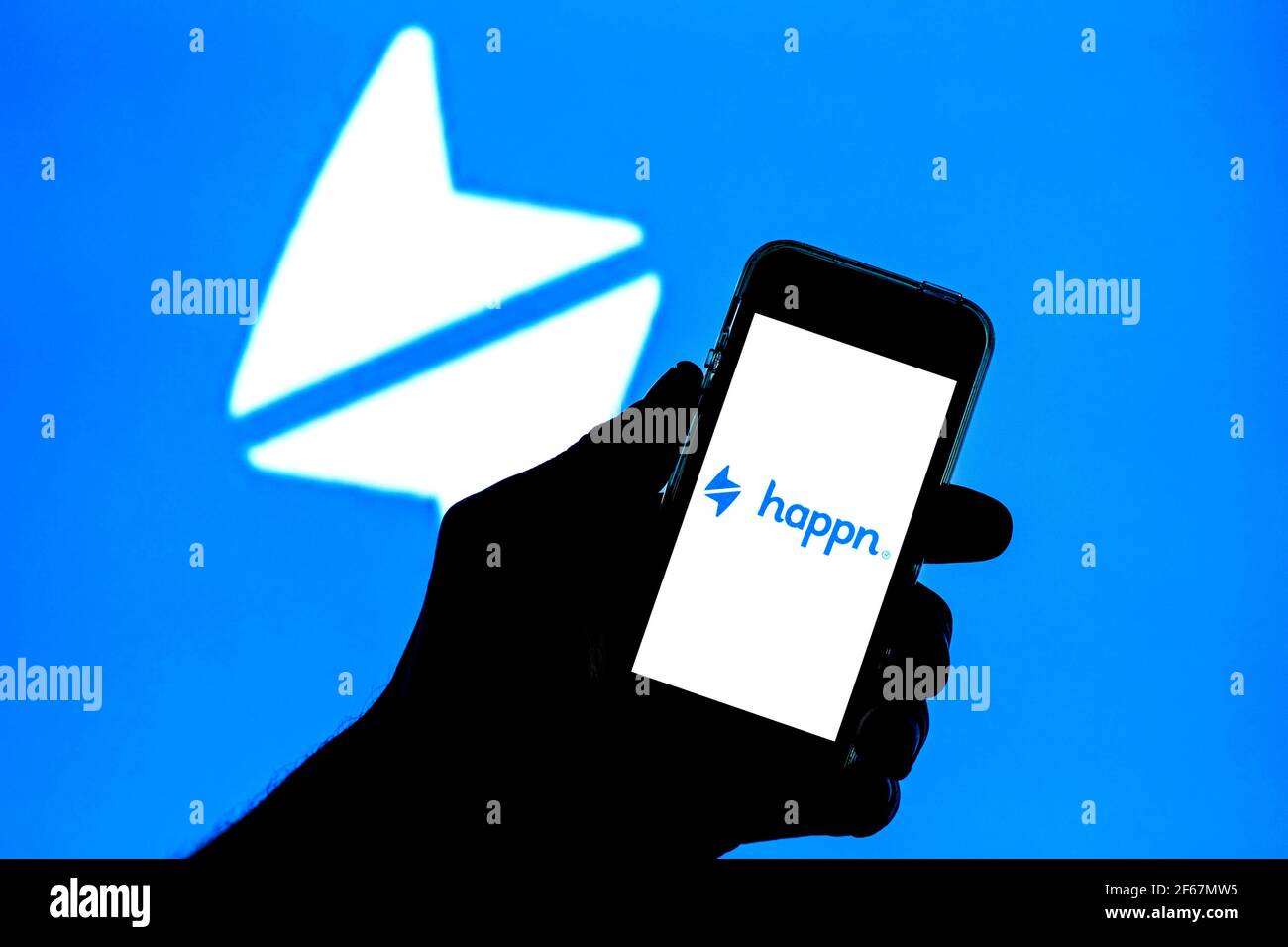 In this photo illustration, the Happn app seen displayed on a smartphone screen and a Happn logo ...