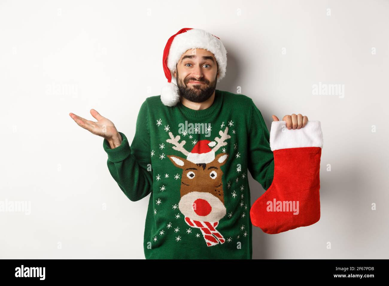 Xmas and winter holidays concept. Confused guy in Santa hat holding ...