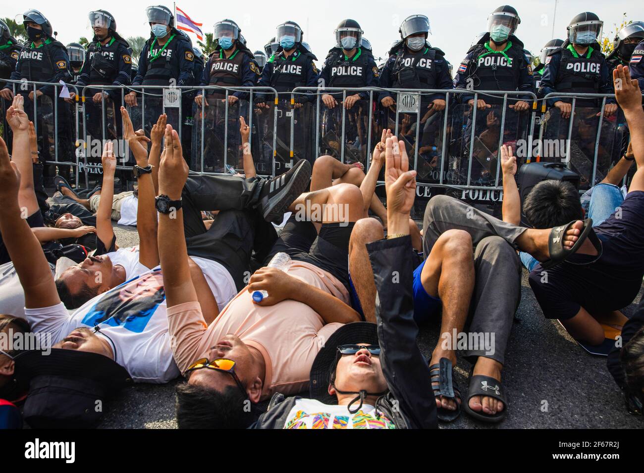 Protesters laying down make three finger salutes at crowd control ...