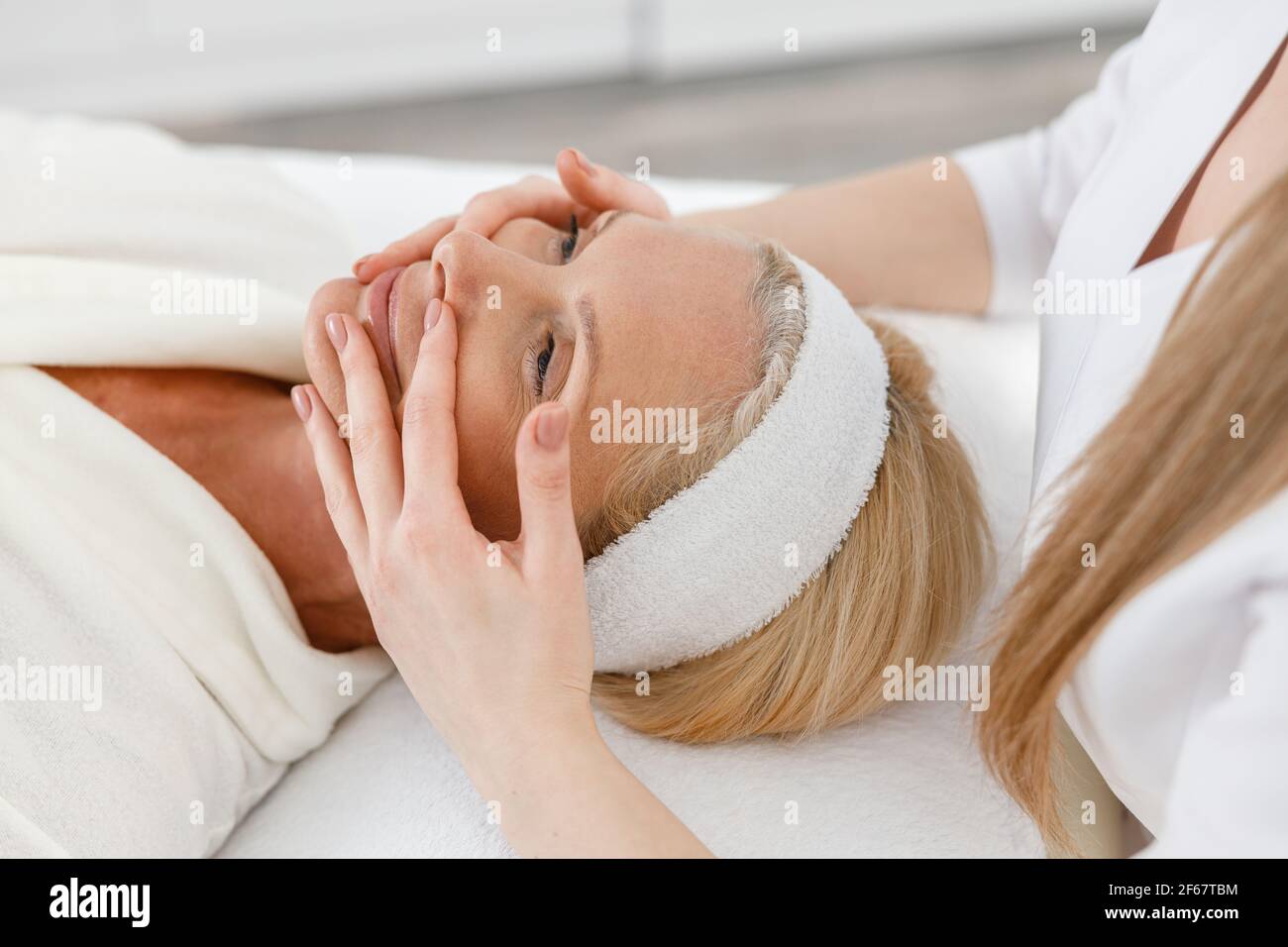 Senior female is lying on back, getting face lifting massage. Facial ...