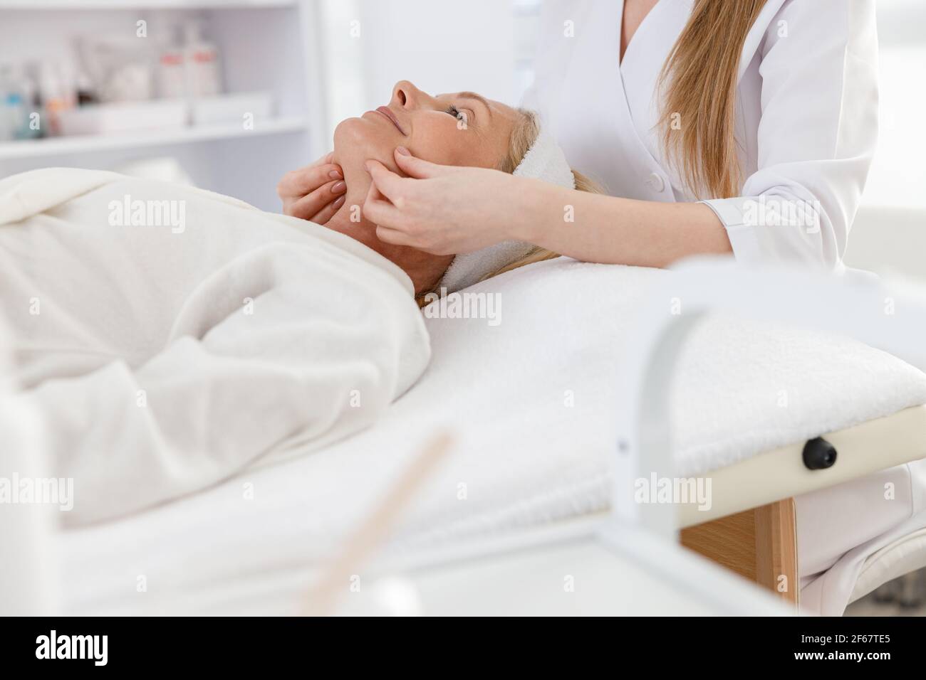 Senior female is lying on back, getting face lifting massage. Facial ...