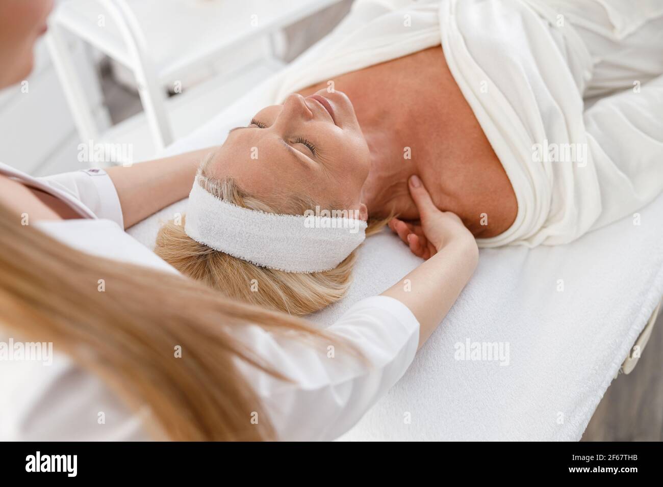 Senior female is lying on back, getting face lifting massage. Facial ...