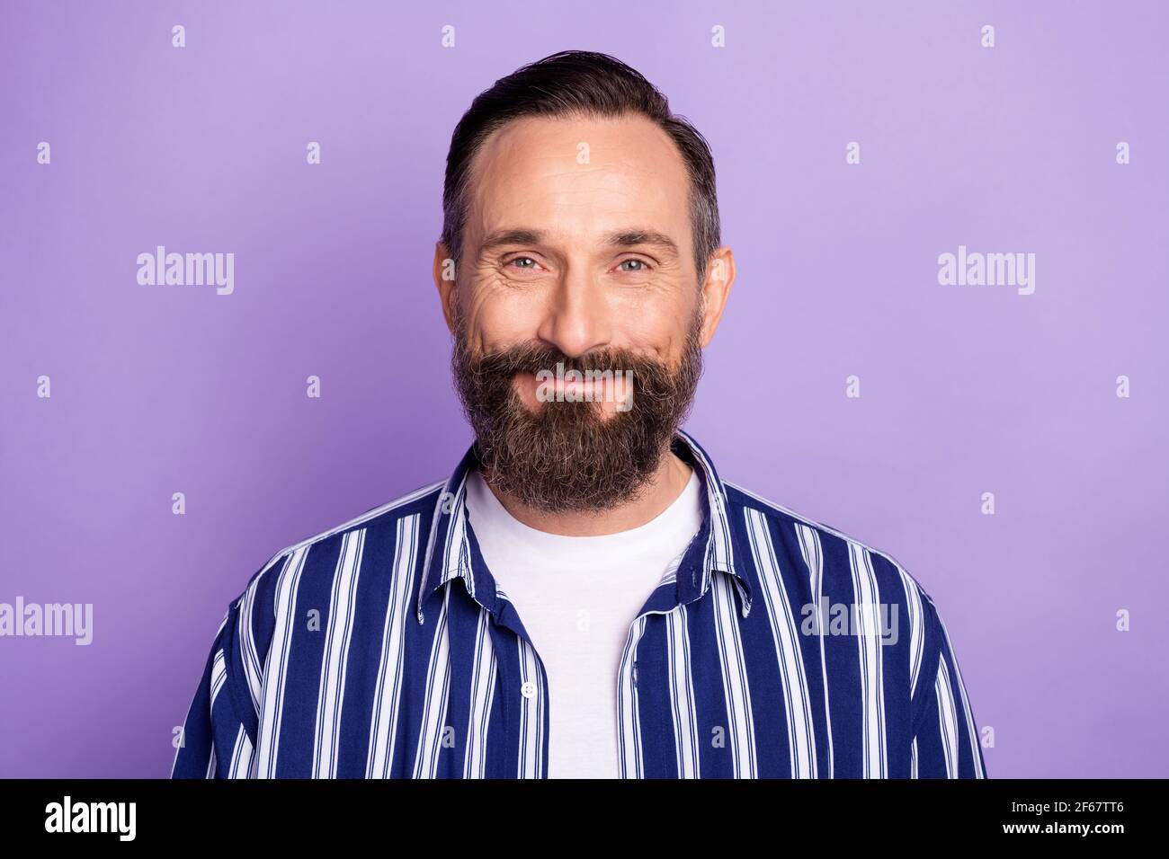 Portrait of positive mature man smiling in camera isolated over violet ...