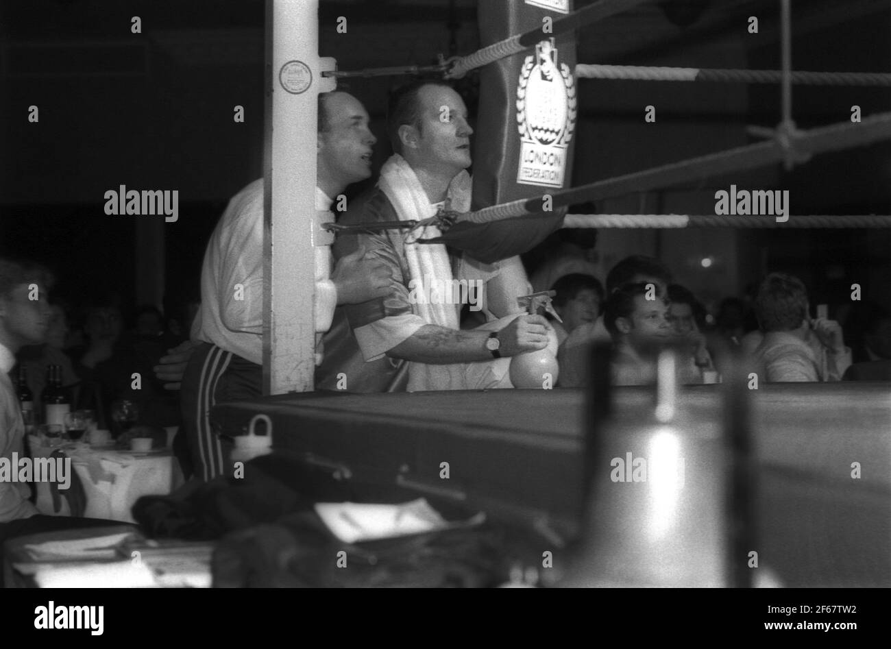Trainer and corner man watch their boxer fight at boxing fight night ...