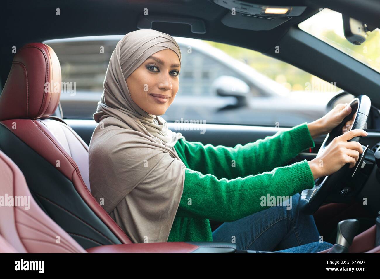 Smiling muslim woman driving her new car in urban city Stock Photo - Alamy