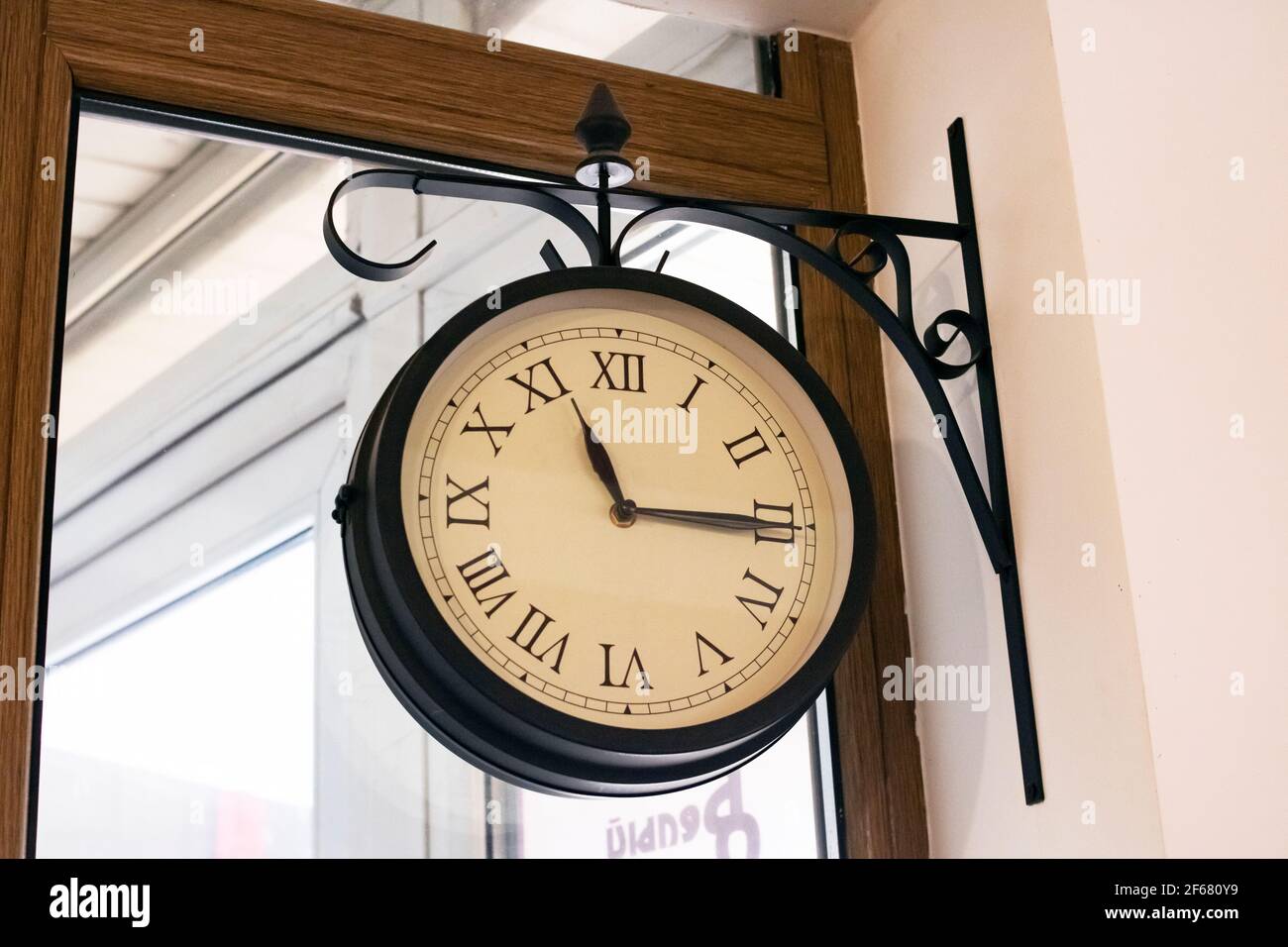 Retro clock with arrows on the wall Stock Photo - Alamy