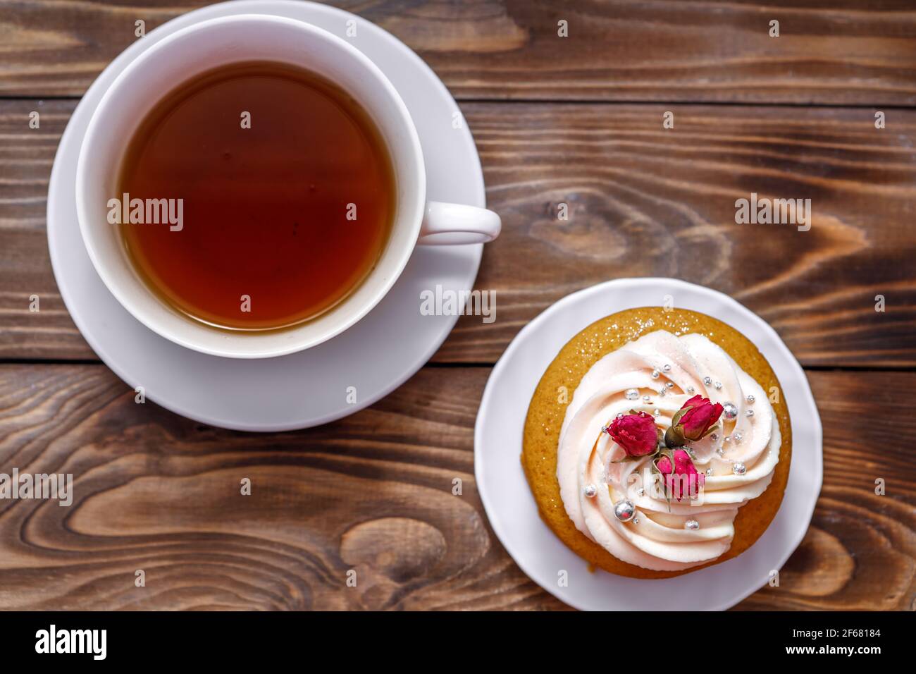 Sponge cake with cream, decorated with small flowers and a cup of tea ...