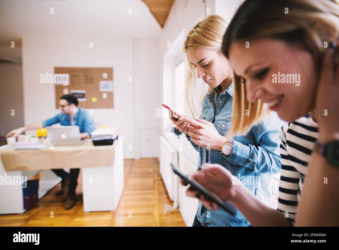 Two young women using mobile for a break in in the bright office Stock ...