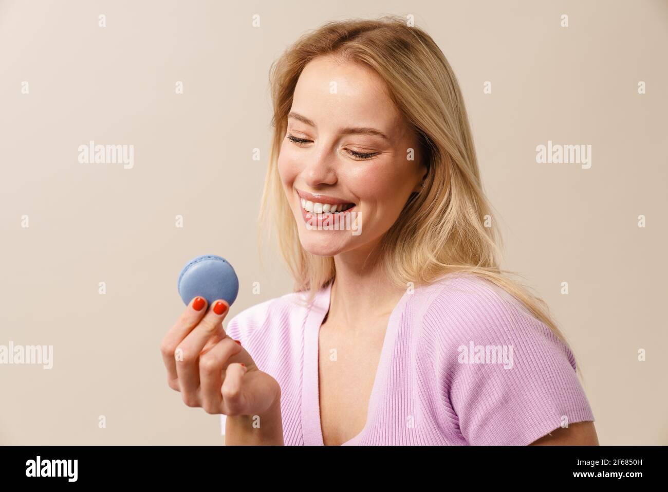Happy beautiful girl smiling while posing with macaroon isolated over ...