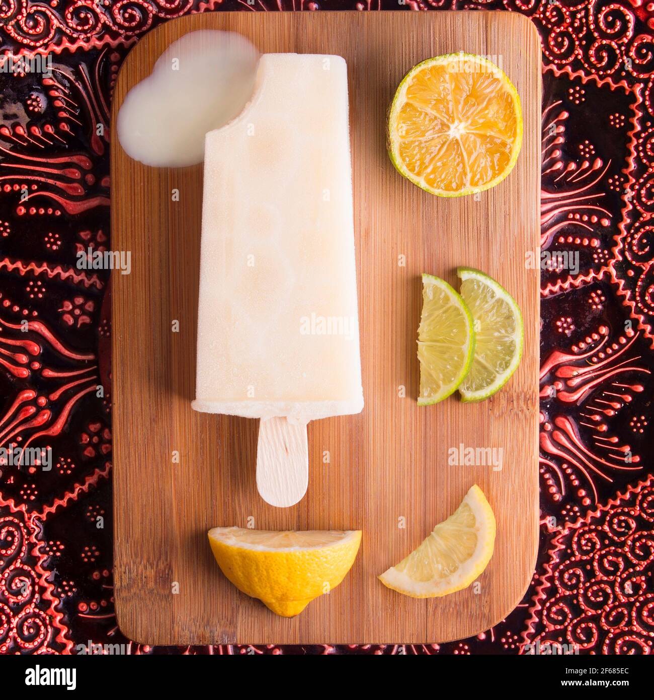 A lemon Mexican paleta popsicle filled with condensed milk on a wooden ...