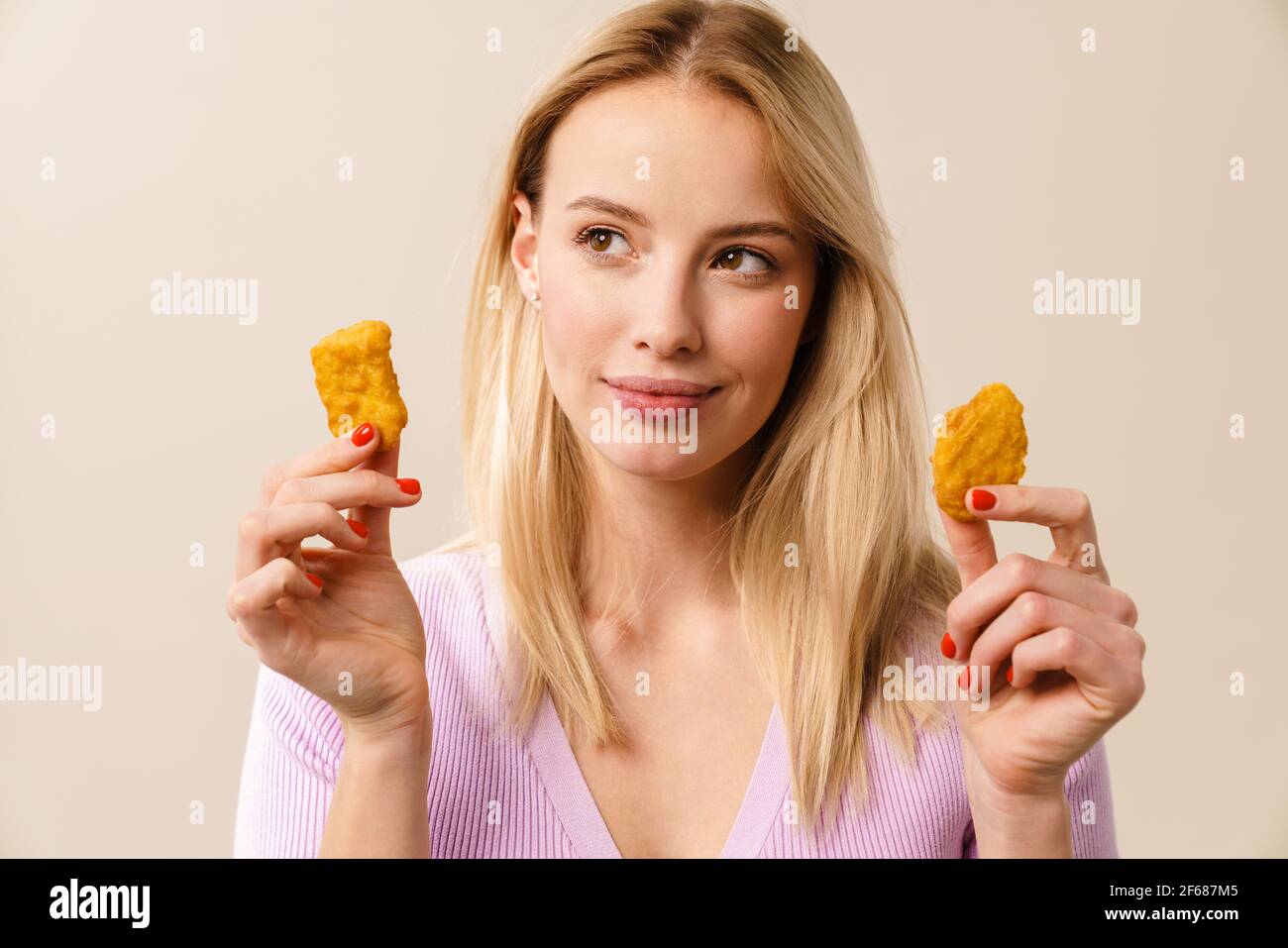 Pleased beautiful girl smiling while posing with nuggets isolated over ...