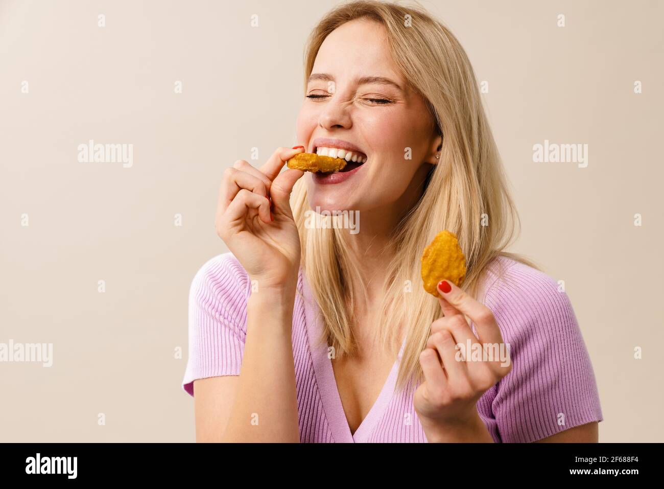 Cheerful beautiful girl laughing while eating nuggets on camera ...