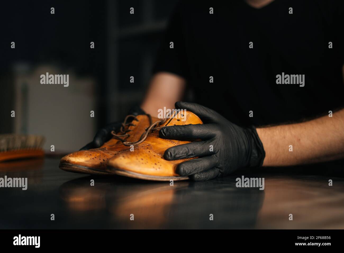 Close-up side view of hands of shoemaker shoemaker in black gloves ...