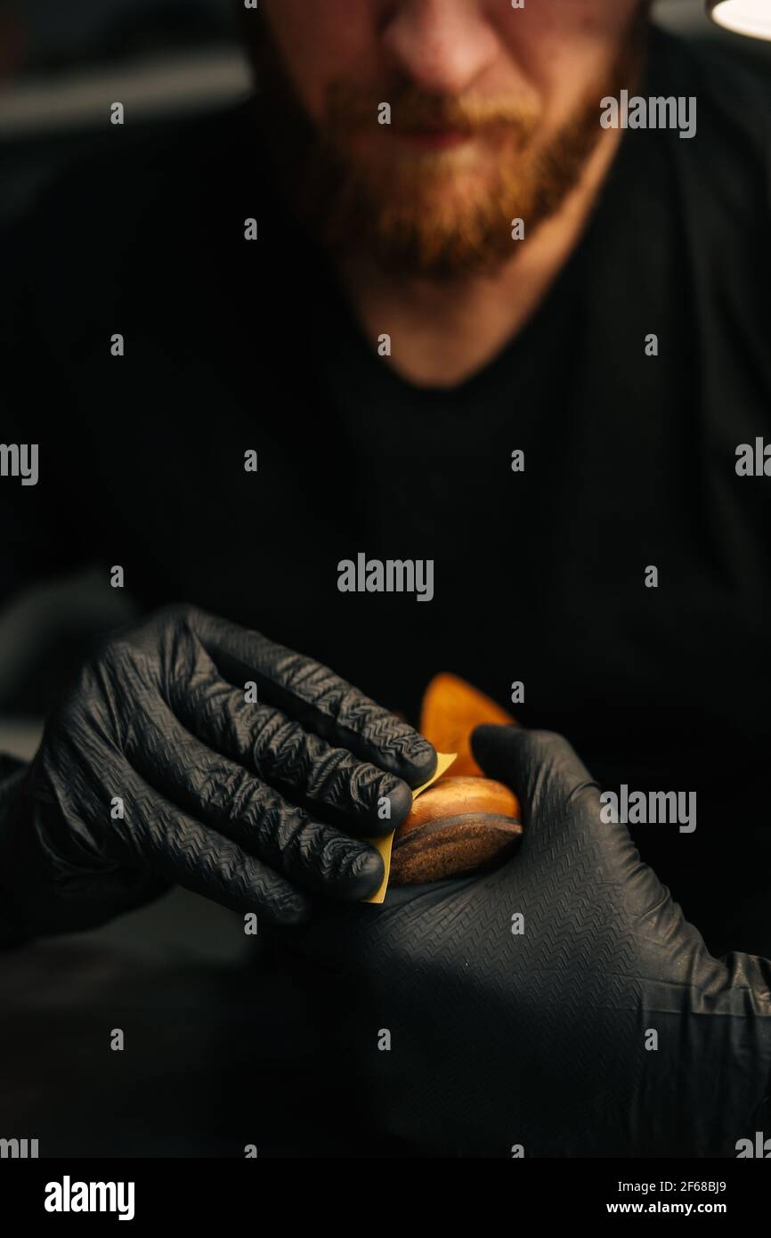Close-up front view of shoemaker wearing black latex gloves cleaning ...