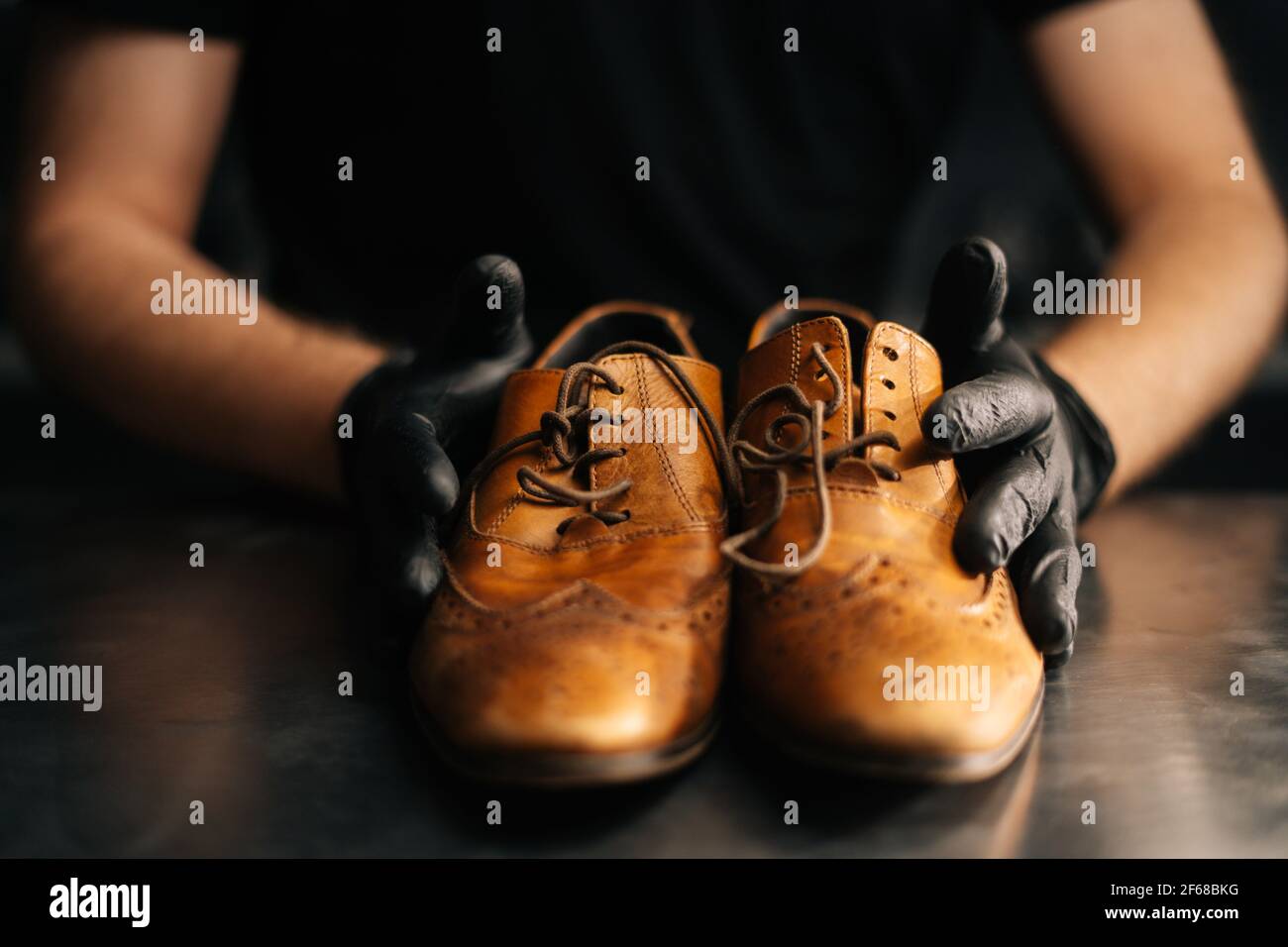 Close-up front view of hands of shoemaker shoemaker in black gloves ...