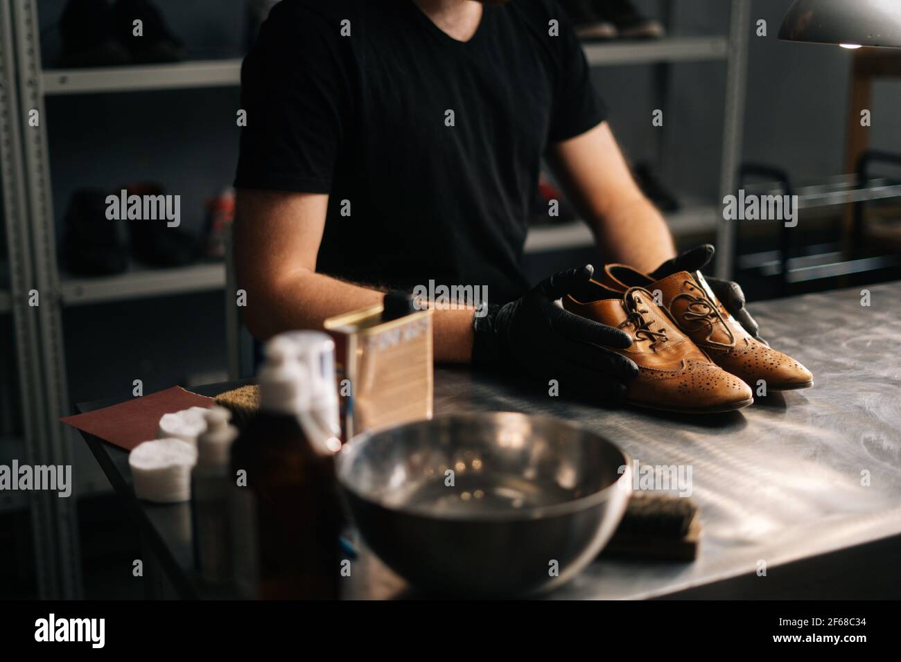 Side view of hands of shoemaker shoemaker in black gloves holding old ...