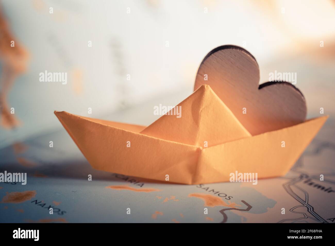 isolated origami yellow boat with wooden heart on world map. travel ...