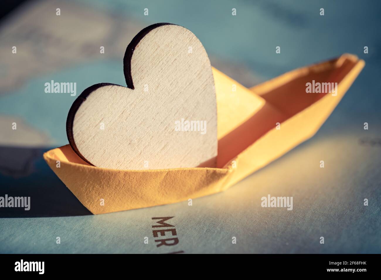 isolated origami yellow boat with wooden heart on world map. travel ...