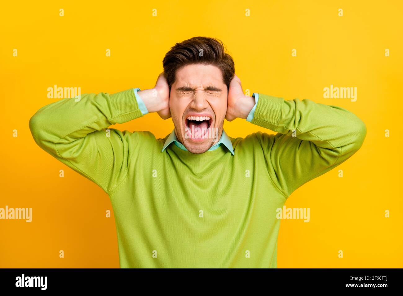 Close-up portrait of outraged brown-haired guy closing ears yelling ...