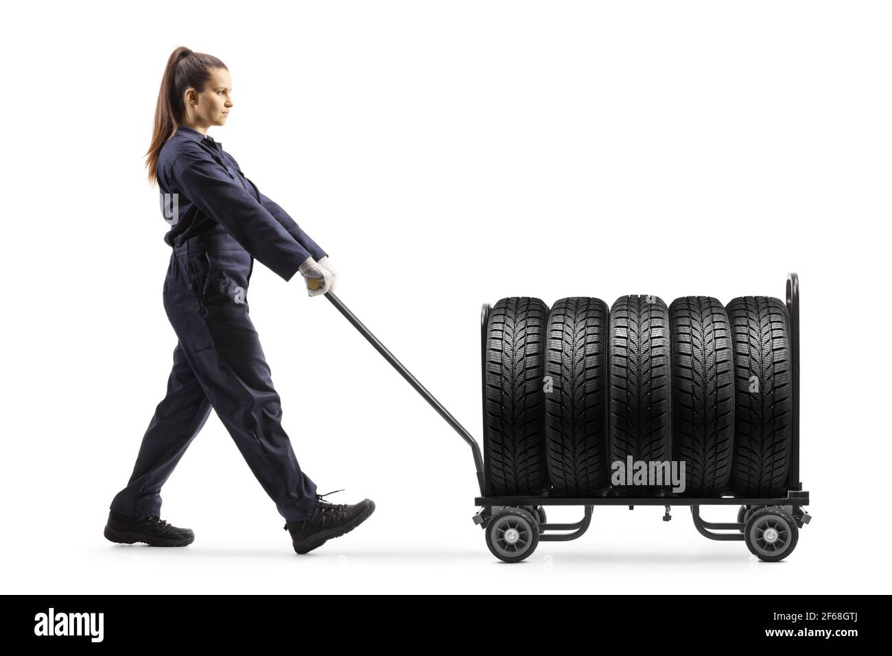 Female mechanic pushing vehicle tires on a hand truck isolated on white ...