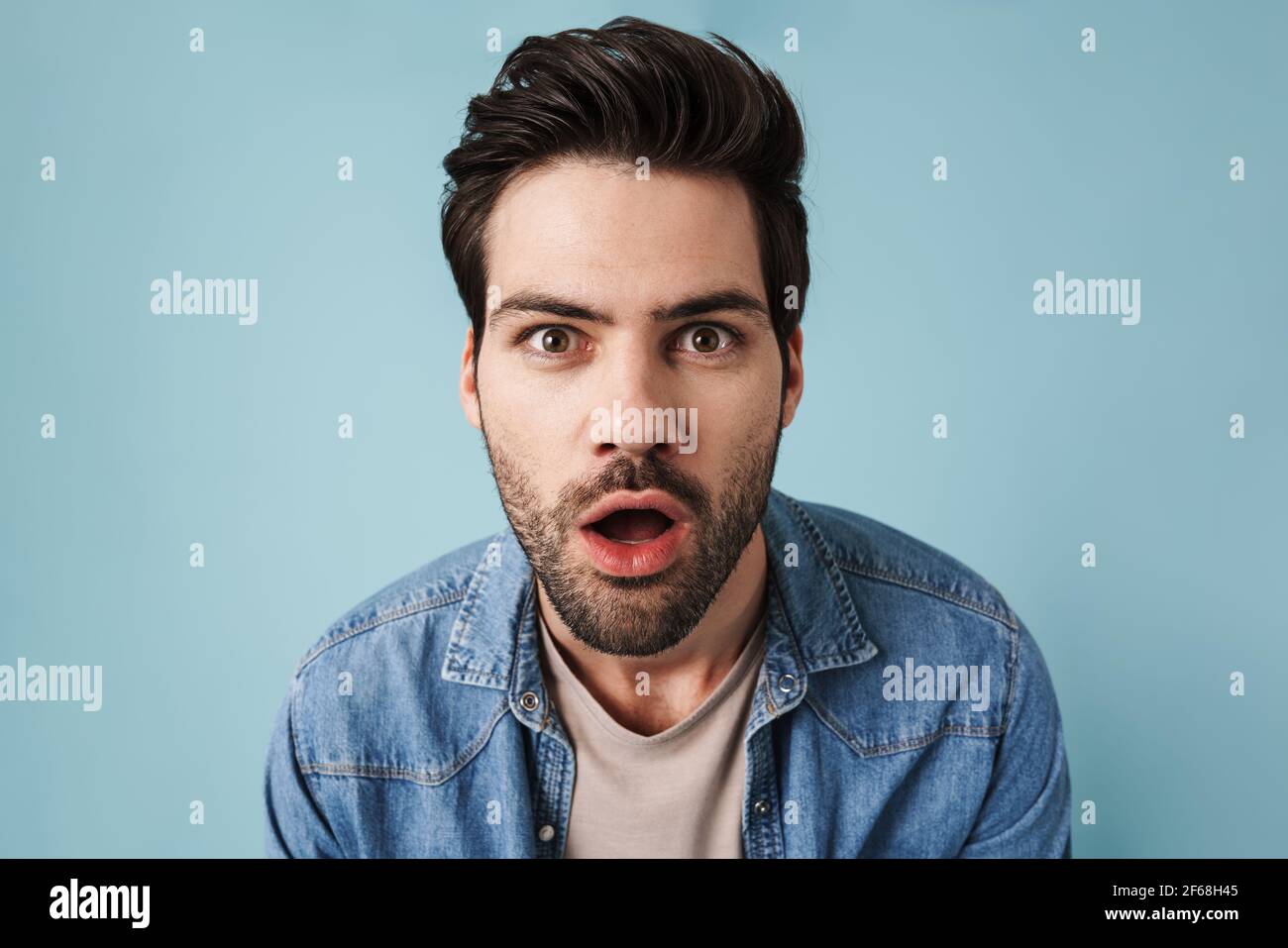 Young handsome shocked man expressing surprise on camera isolated over ...