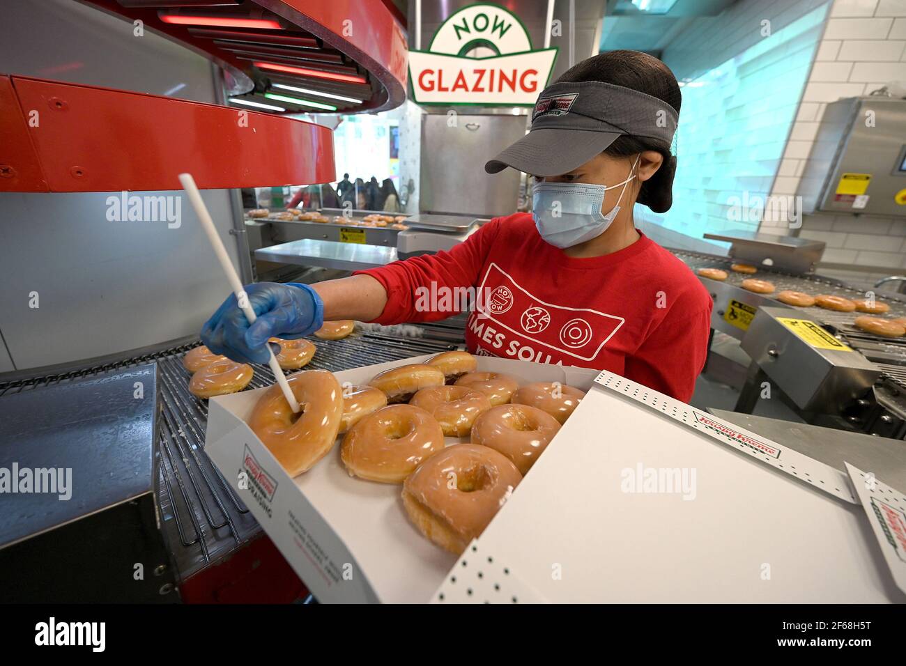“Glazing expert” Taji Lewis prepares a box of a dozen donuts inside the ...