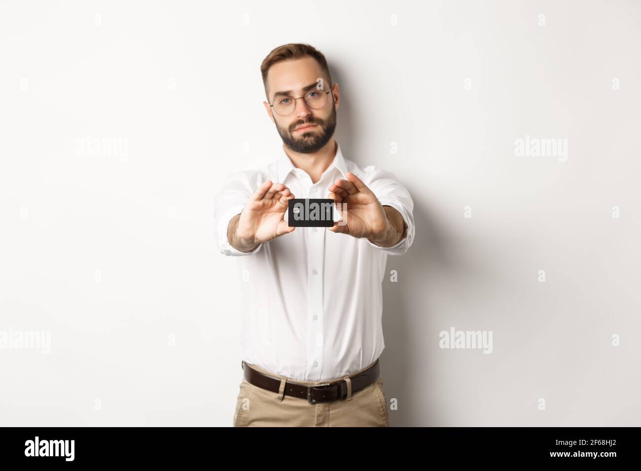 Serious businessman showing credit card, standing over white background ...