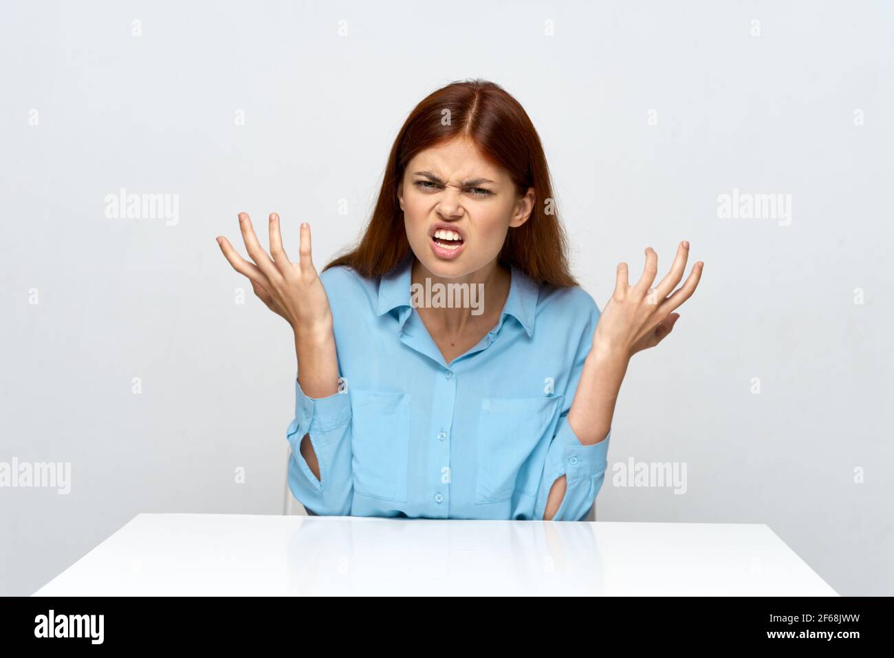 emotional woman in a shirt sits at the table gesture with the hands of ...