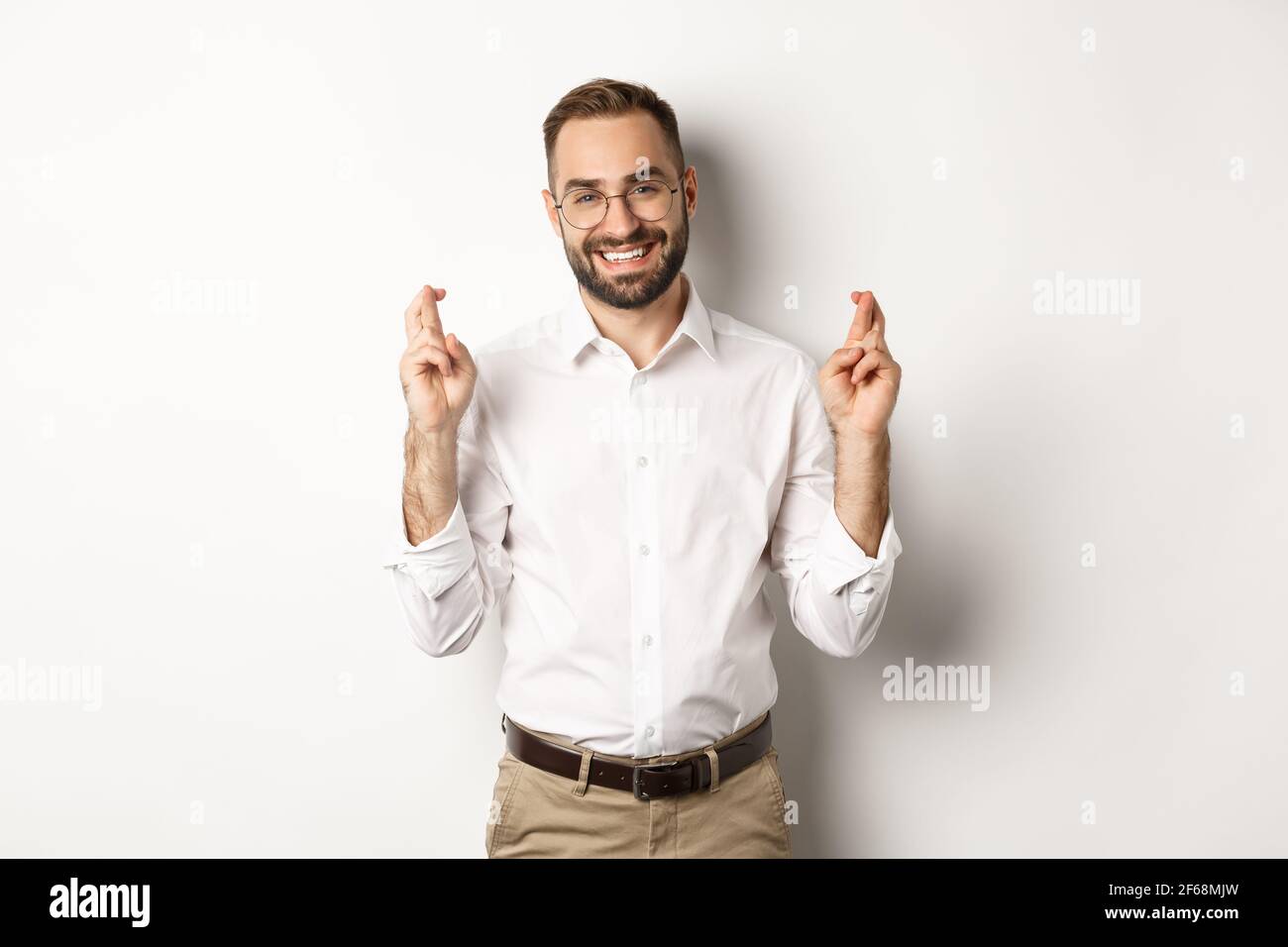 Hopeful optimistic man making a wish, cross fingers and praying ...