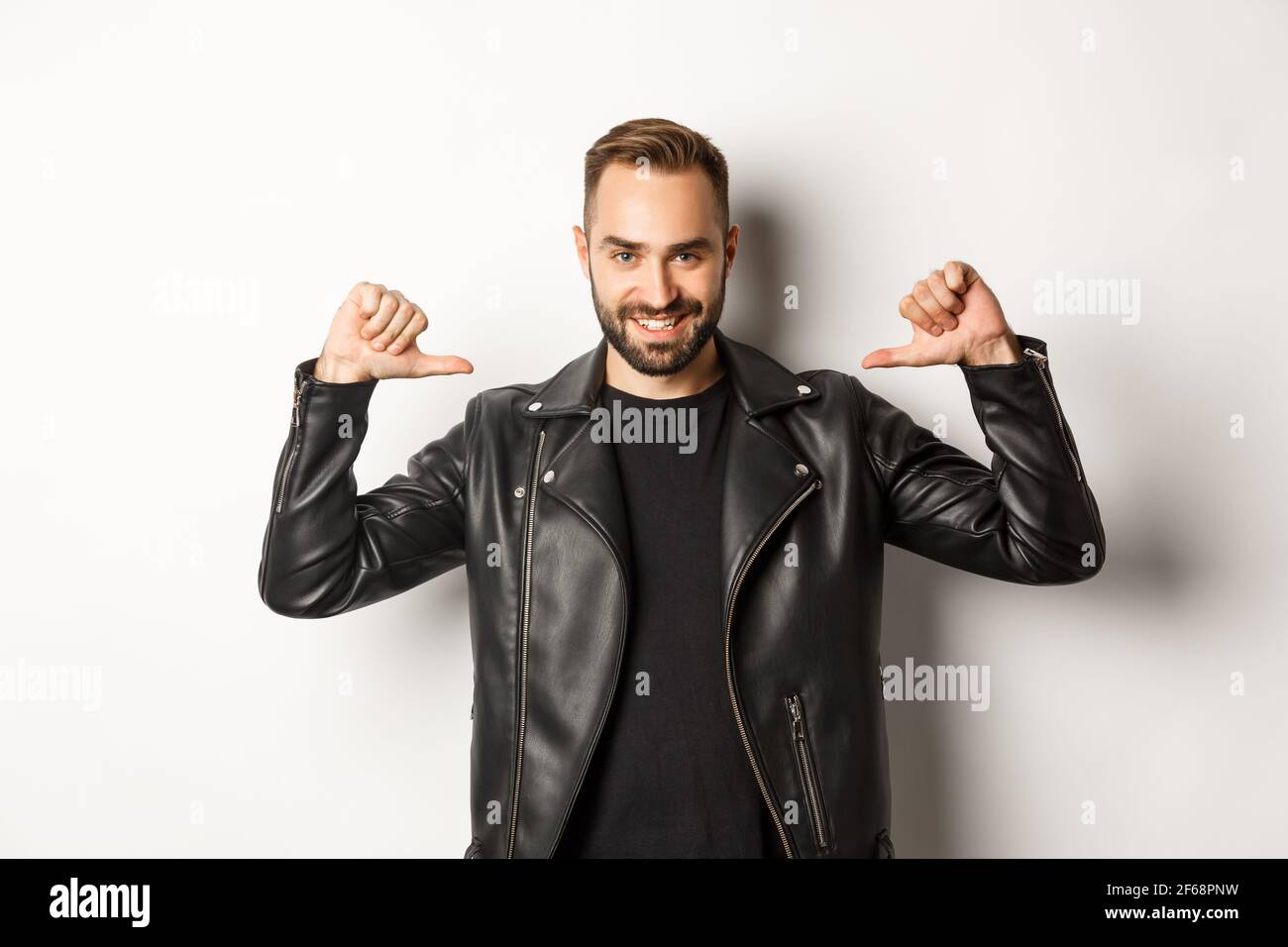 Confident handsome man wearing black leather jacket, pointing at ...